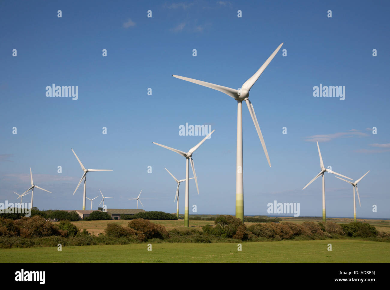 11 wind turbines and farm outbuildings on wind farm against blue cloudy ...