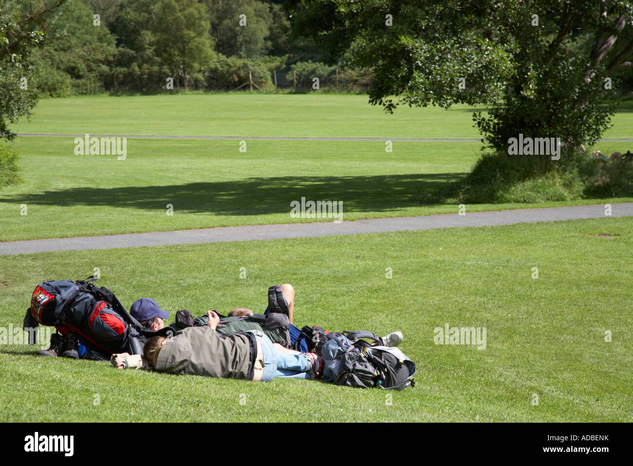 tourists lying on the grass soaking up the sun with backpacks open ...
