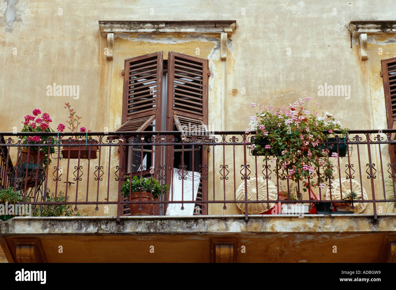 Elegant ironwork balcony with flowerpots and old wooden shutters ...