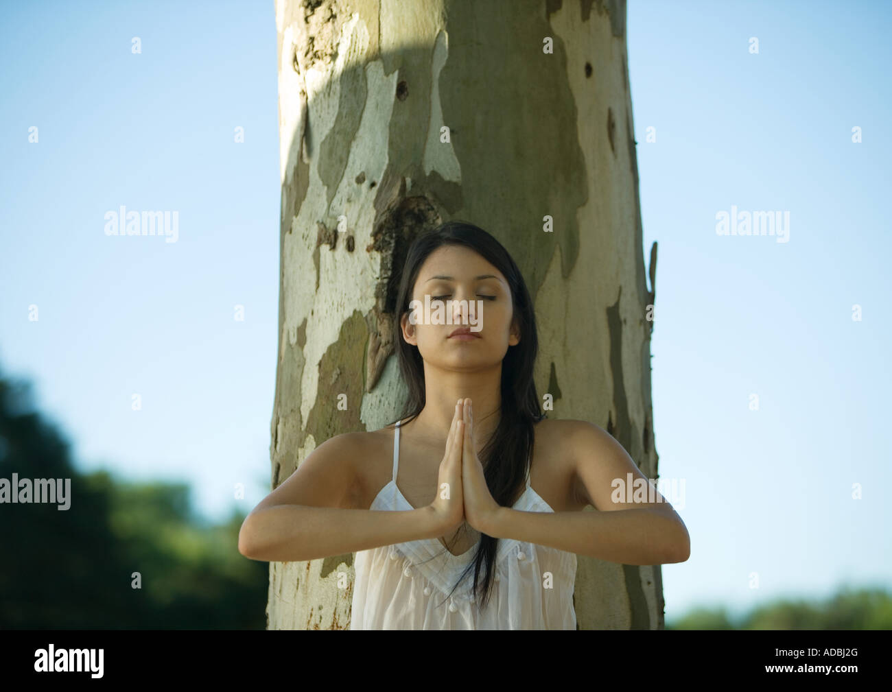 Woman leaning against tree, doing yoga pose Stock Photo - Alamy