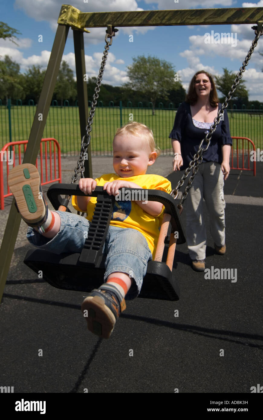 Young child being pushed on swing hi-res stock photography and images ...
