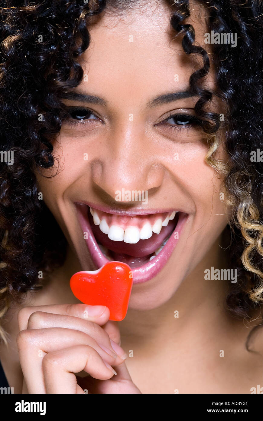 a beautiful woman biting a candy heart Stock Photo - Alamy