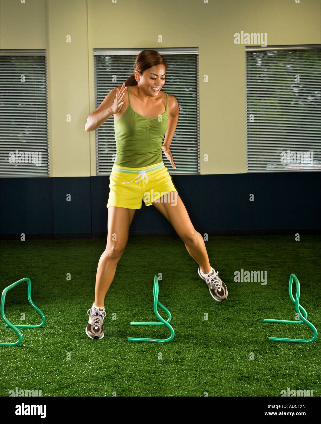 Asian female jumping over hurdles sideways inside Stock Photo - Alamy