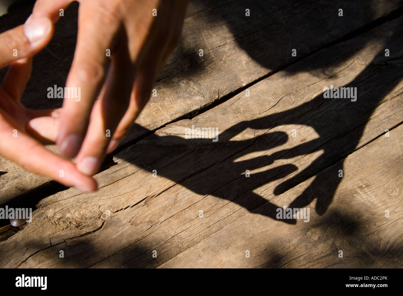 Male hands casting shadow over wooden table Stock Photo - Alamy