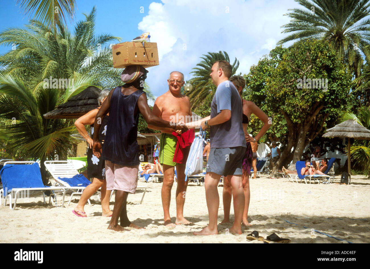 Local Aloe Vera salesman shaking hands with holidaymaker on beach in ...