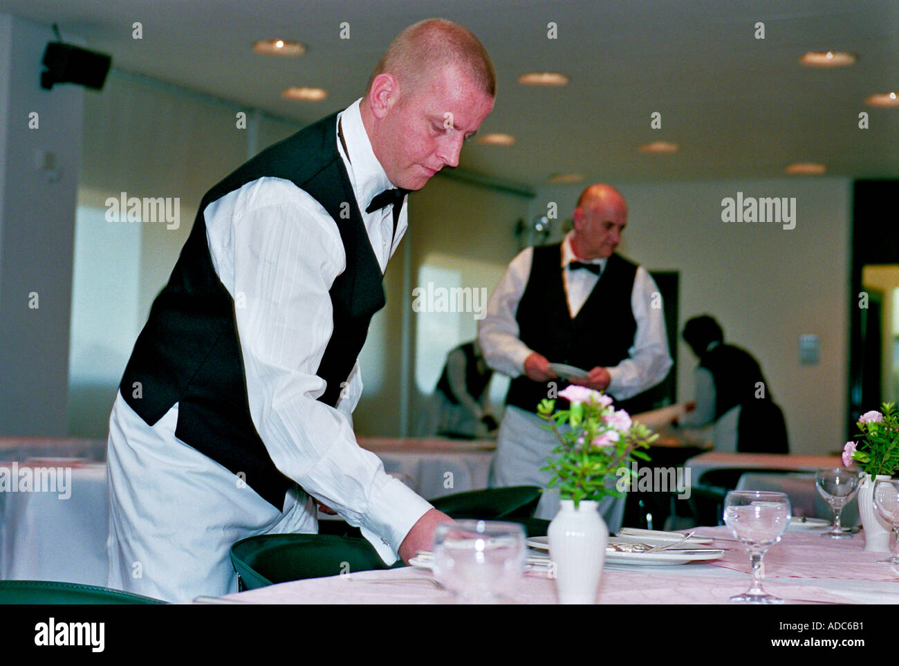 Two waiters prepare restaurant for service Stock Photo - Alamy