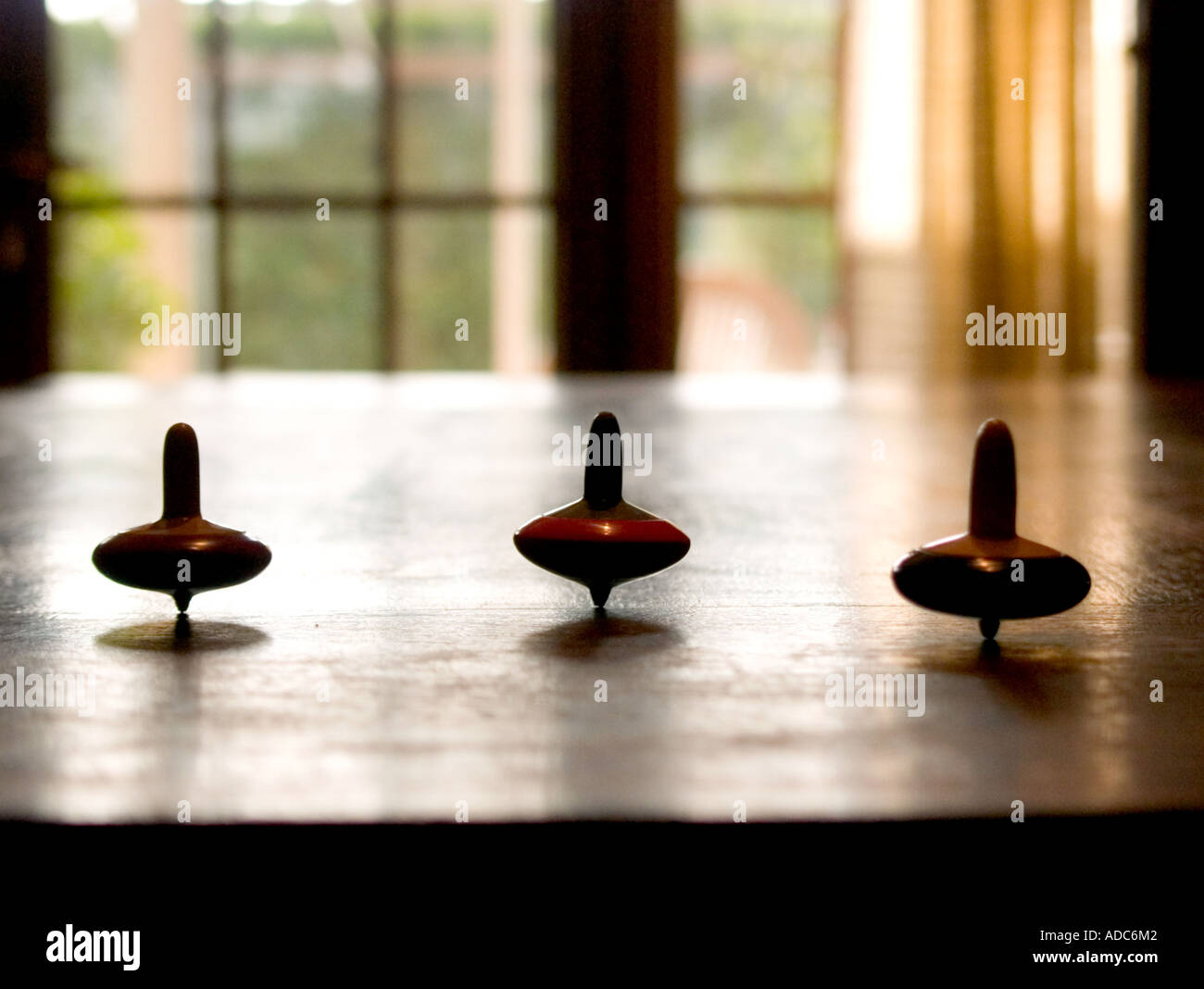 three spinning tops spinning in line on kitchen table Stock Photo - Alamy