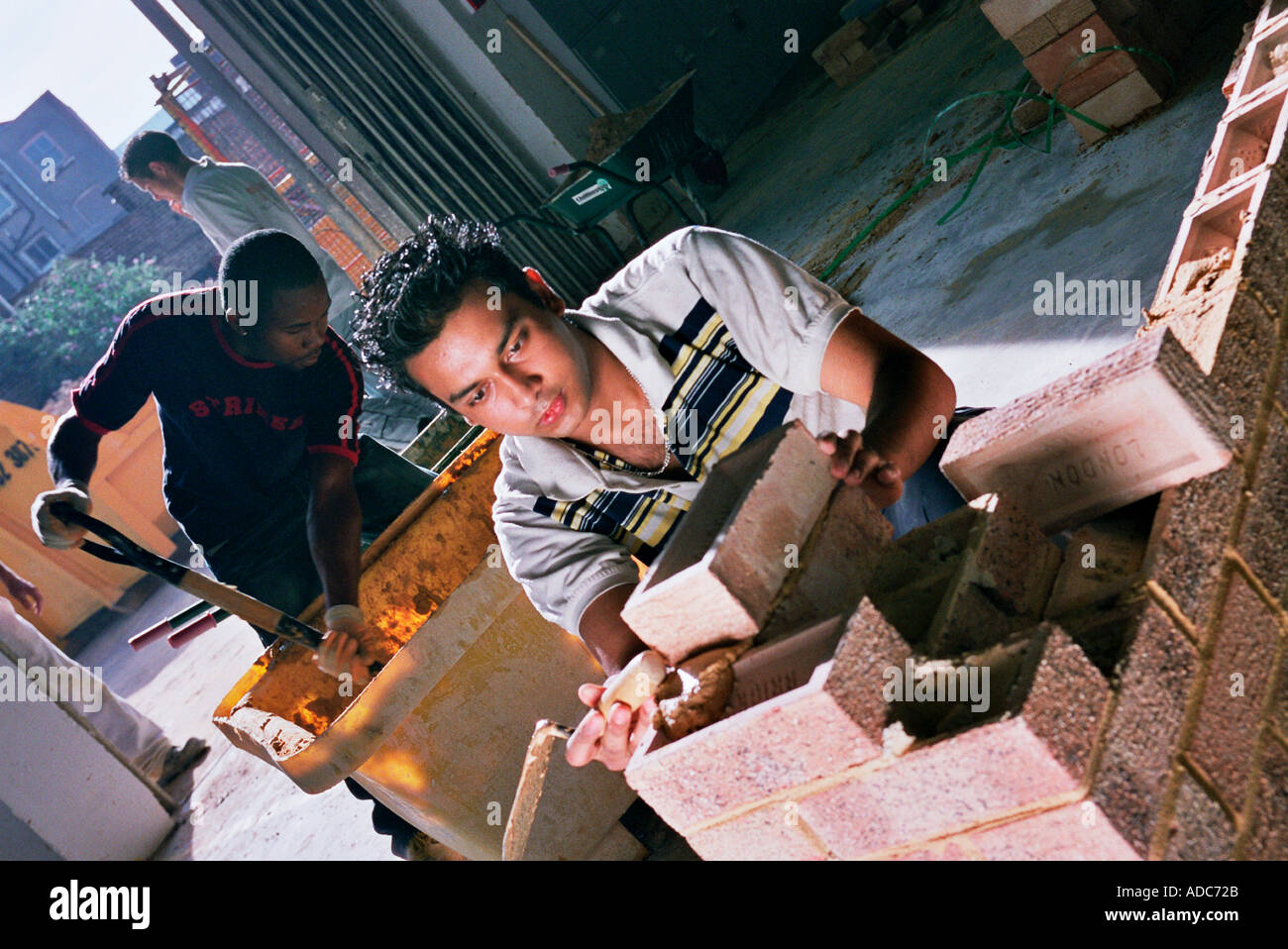 two trainee builders perfect their bricklaying skills Stock Photo - Alamy
