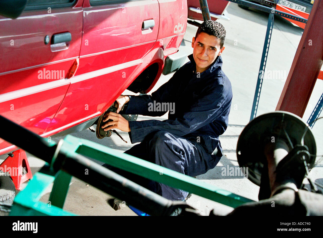 Young attractive male mechanic changes a car wheel at the garage Stock ...