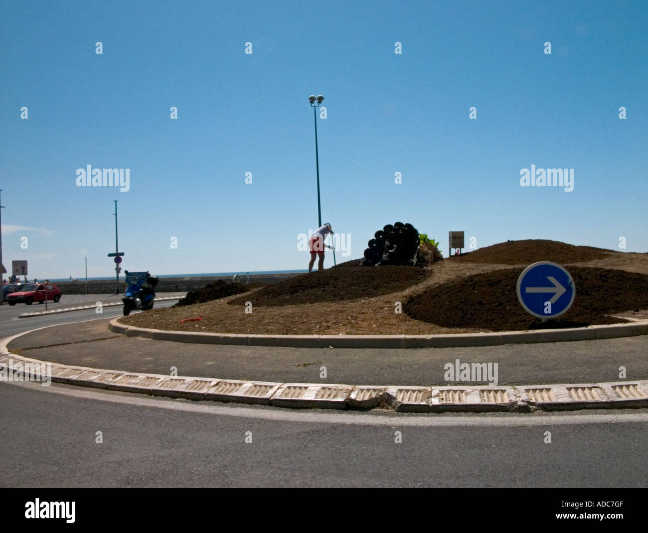 a gardener tends to a some flower beds in the middle of a roundabout in ...