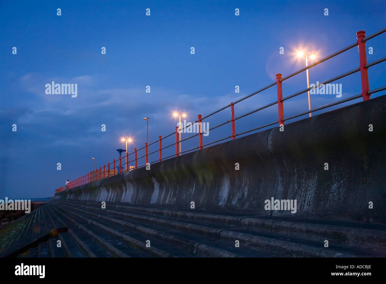 Seafront railings and street lights at dusk with couple kissing in ...