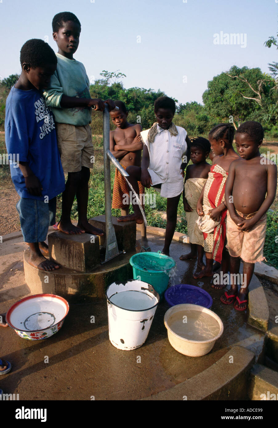 Village children gather around a water pump built with aid from the ...