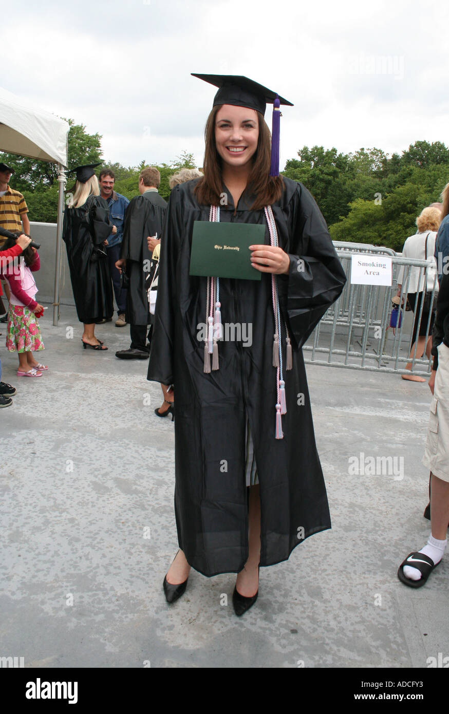 A graduate wearing a cap and gown and holding her diploma Stock Photo ...