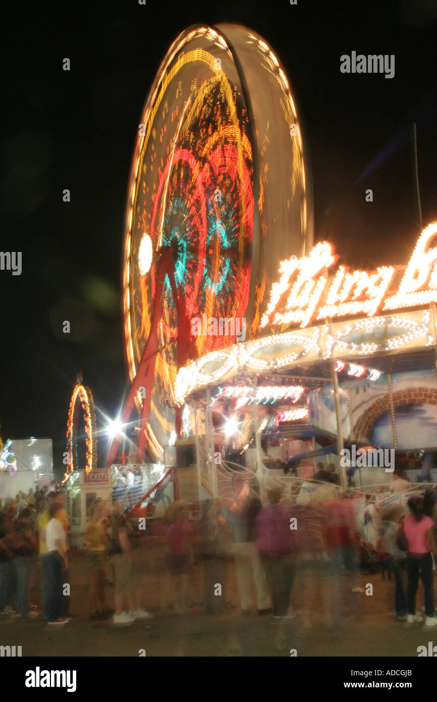 Fair with the lights of the rides and farris wheel turning at night ...