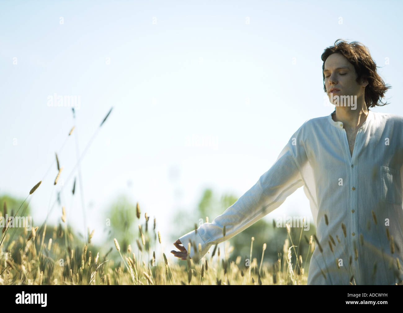 Young male standing in field, arm out, eyes shut Stock Photo - Alamy