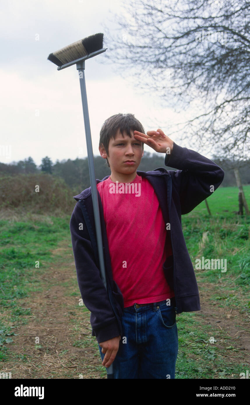 Young boy using a broom and pretending to be a soldier standing to ...