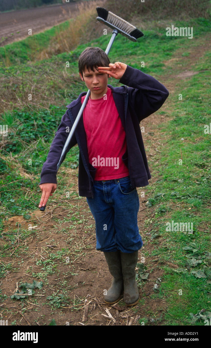 Young boy using a broom and pretending to be a soldier standing to ...