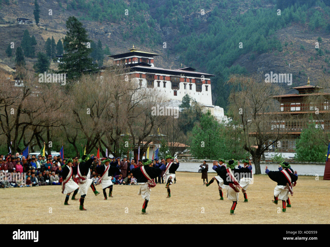 Men in traditional costumes dancing by Paro Dzong a fortress and ...