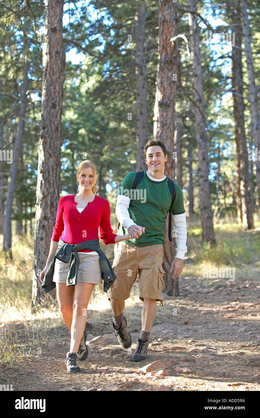 happy Caucasian Couple hold hands while hiking on nature trail through ...