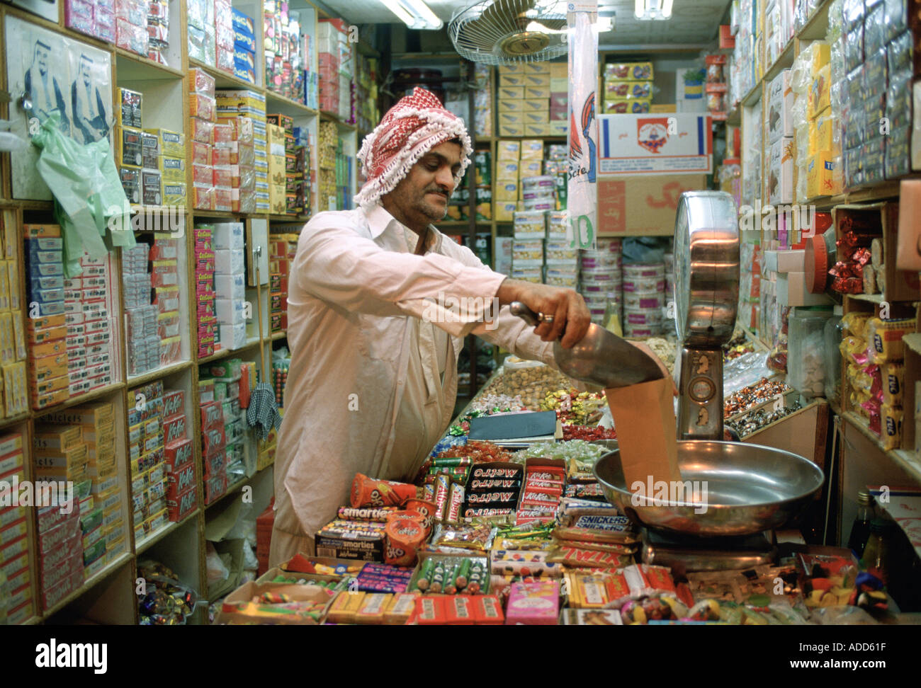 Shopkeeper in sweet and grocery store in Kuwait City in Kuwait weighing ...