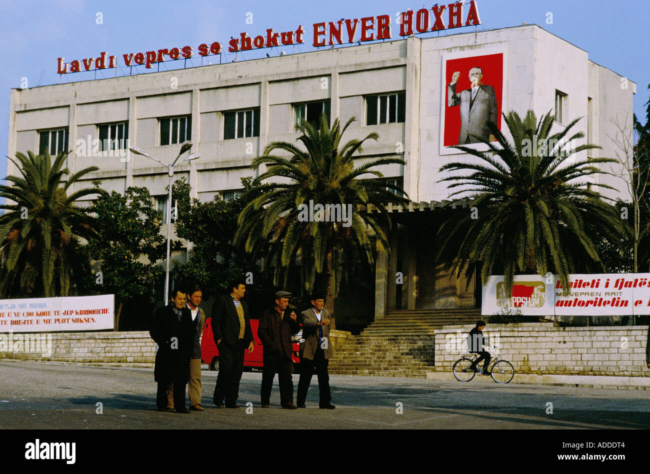 GROUP OF MEN WALKING PAST THE COMMUNIST PARTY BUILDING IN SARANDE, 1990 ...