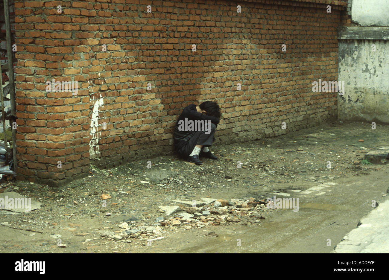 A chinese man is inconsolable in Grief crouching in an alley just of a ...
