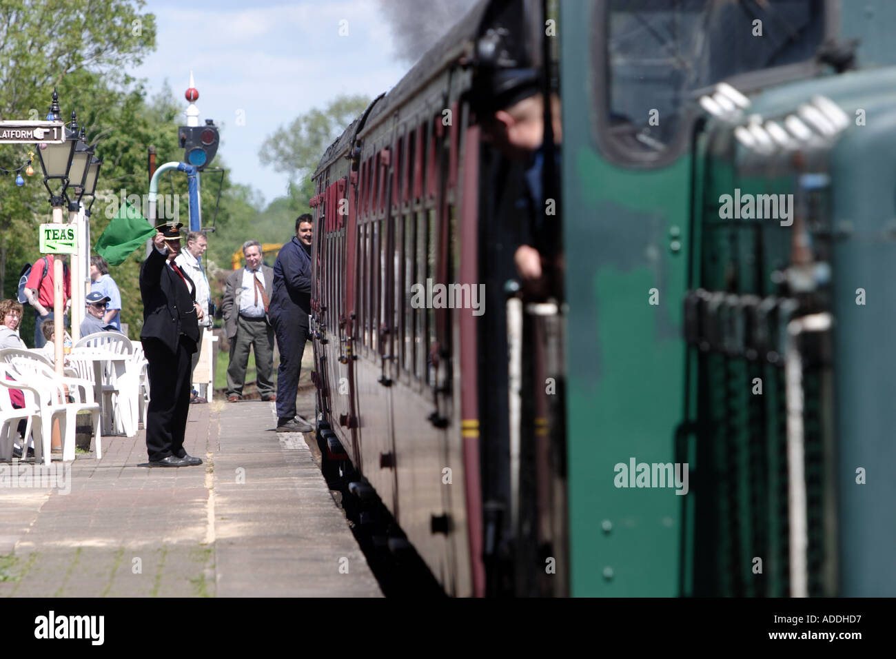 Steam train about to leave the station guard waves a green flag and ...