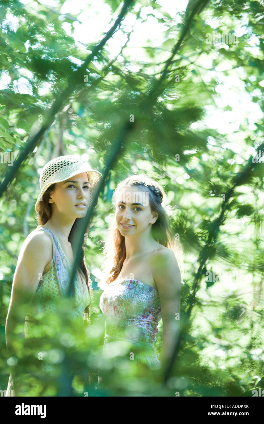 Two young women standing among trees Stock Photo - Alamy