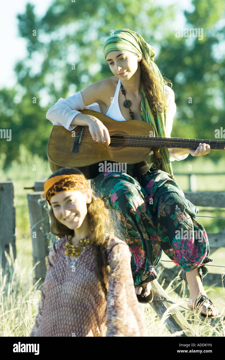 Young hippie women, one playing guitar Stock Photo - Alamy