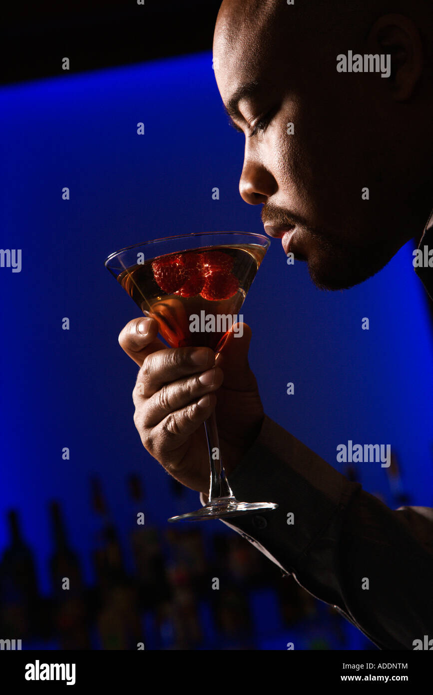 Profile of African American man drinking martini in bar against glowing ...