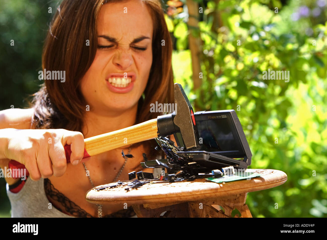 Young woman is destroying a small personal computer with a hammer ...