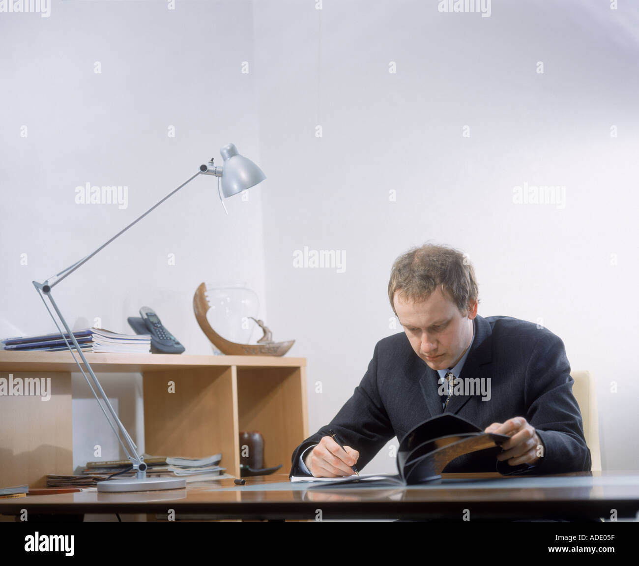 Man in office reading a magazine Stock Photo - Alamy