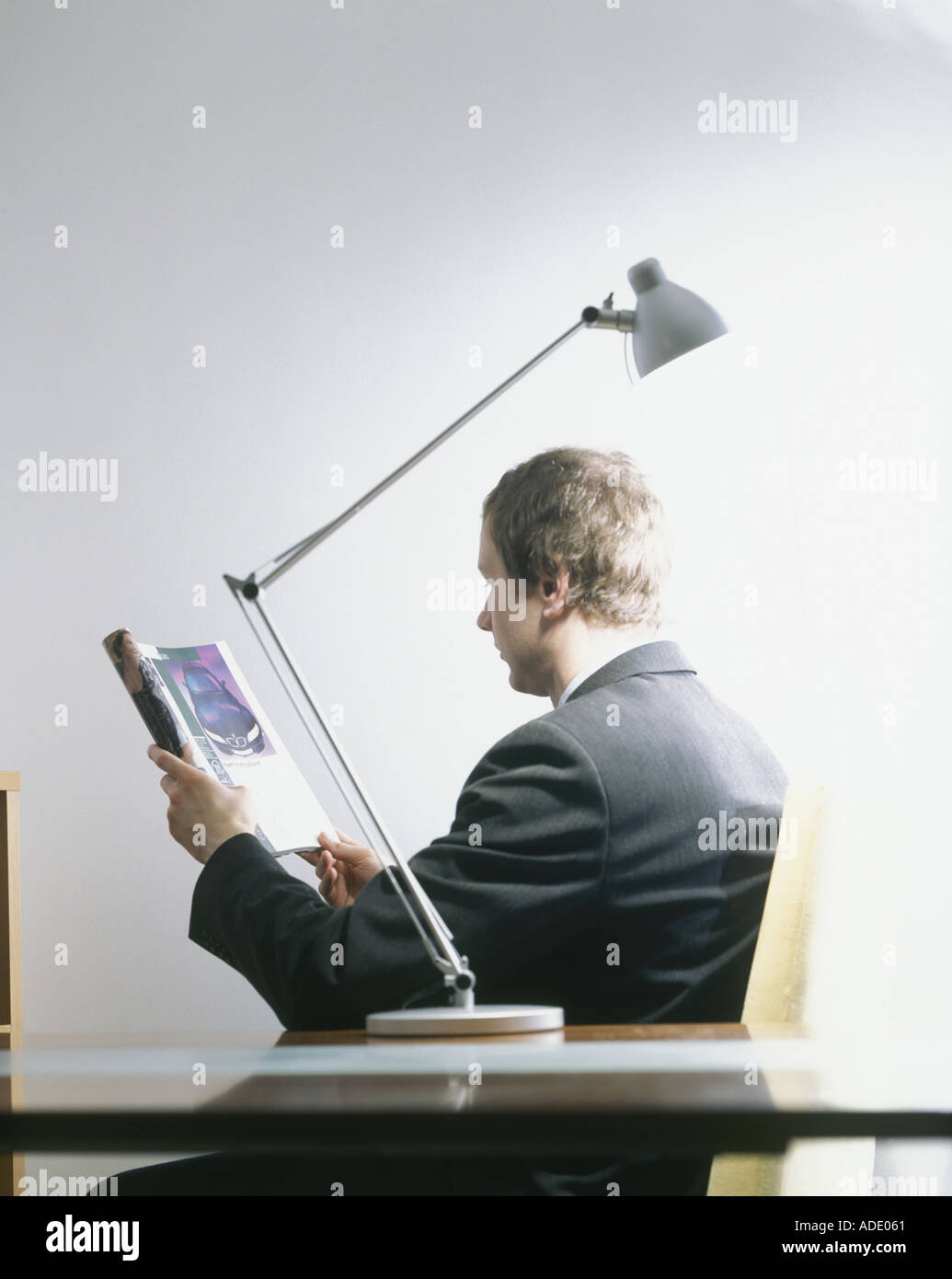 Man at the table reading a magazine Stock Photo - Alamy