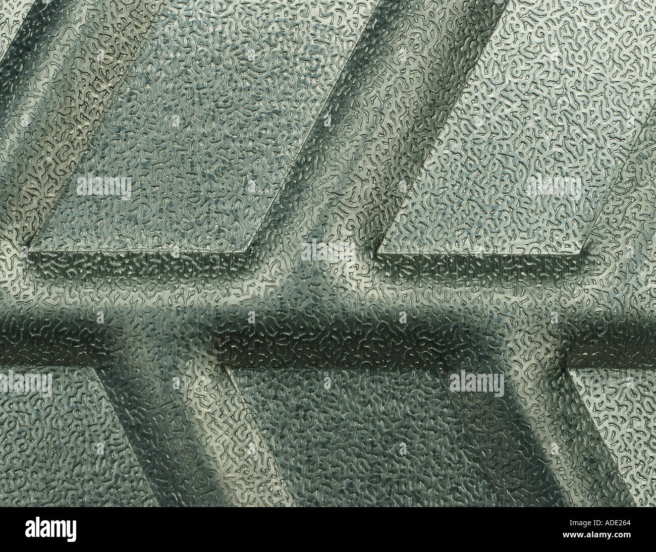 A close up of shiny gray pitted metal with a prominent raised pattern ...