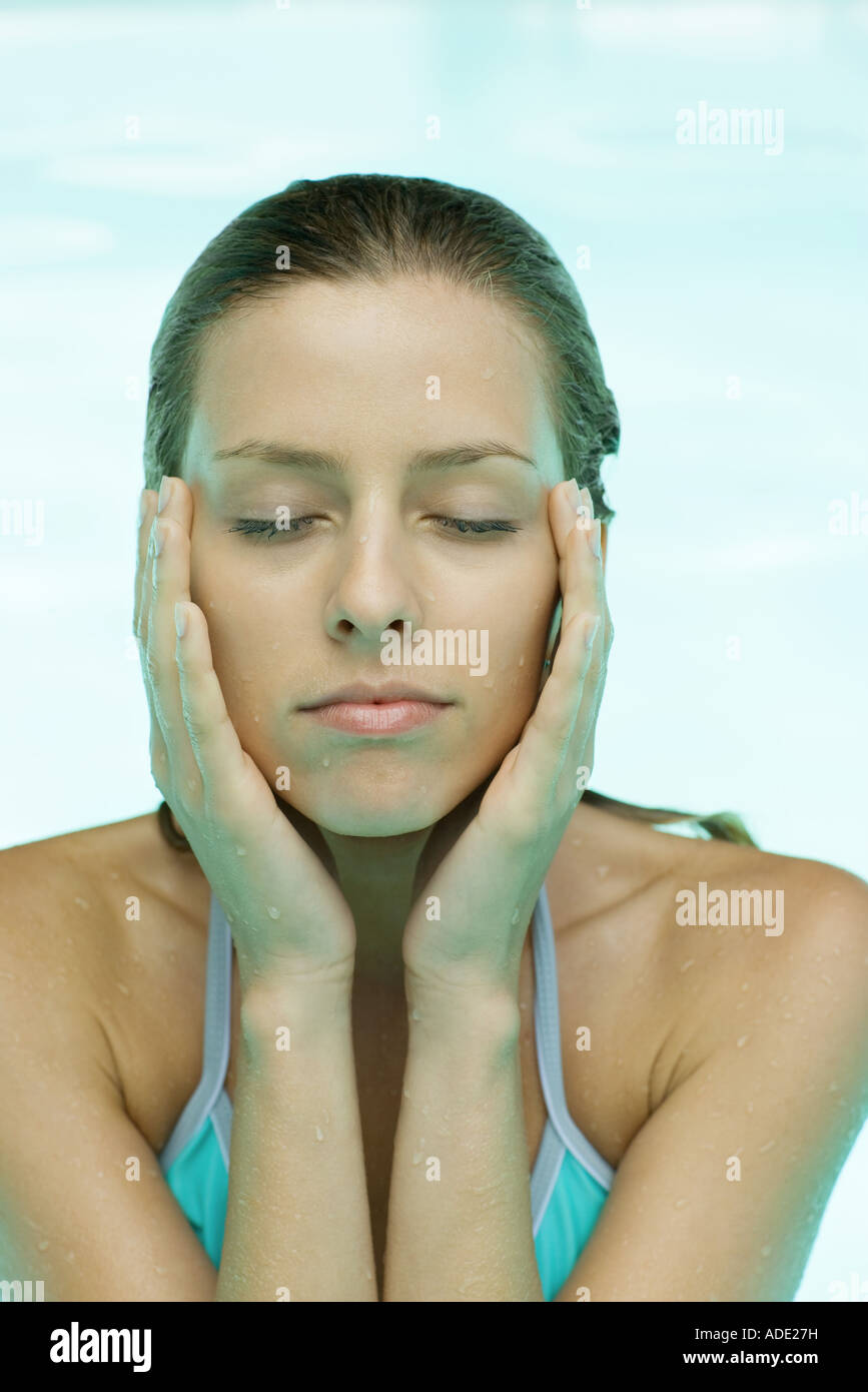 Young woman in pool, eyes closed, hands on side of face Stock Photo - Alamy