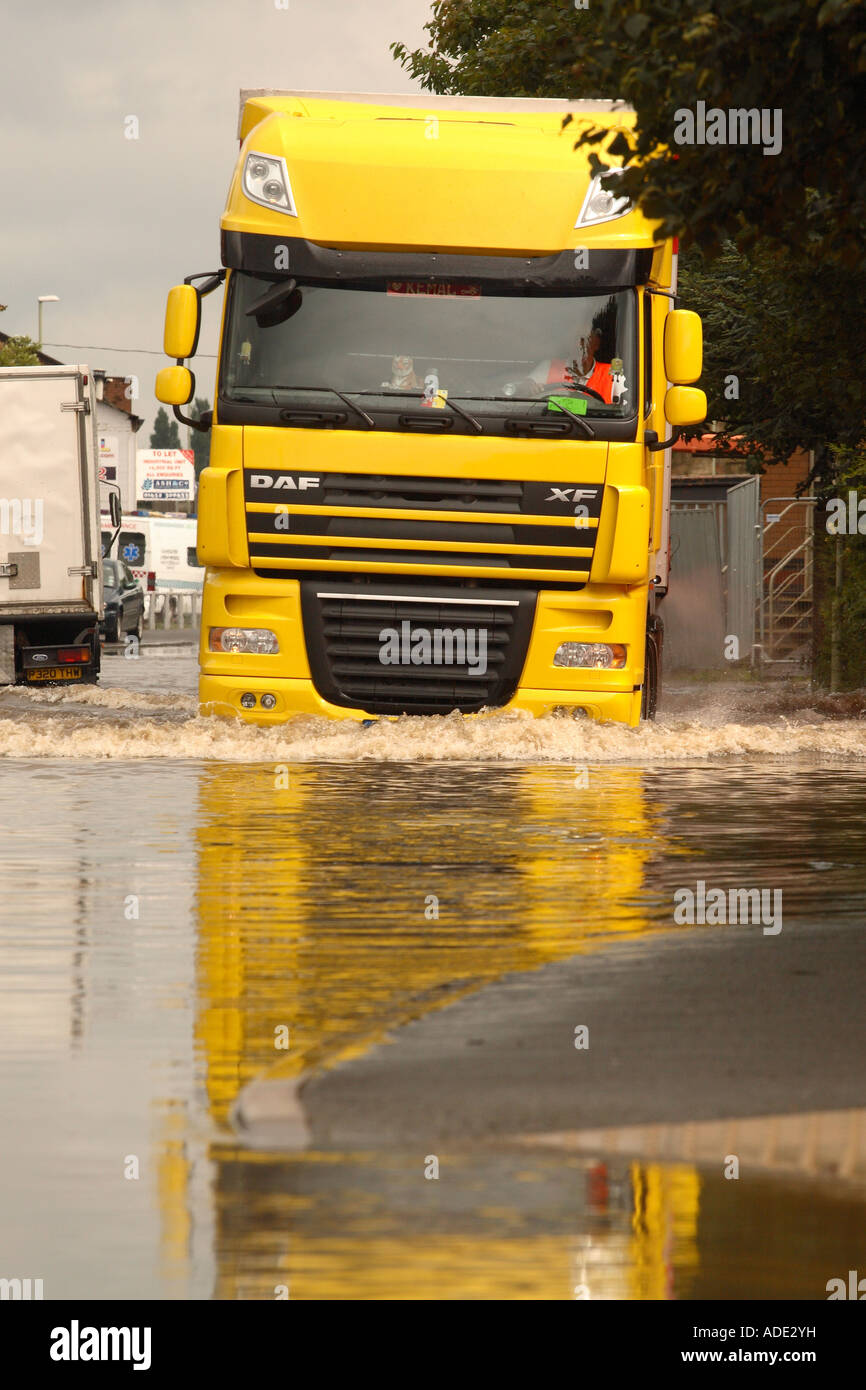 Large articulated heavy lorry driving through deep rain water flooded ...