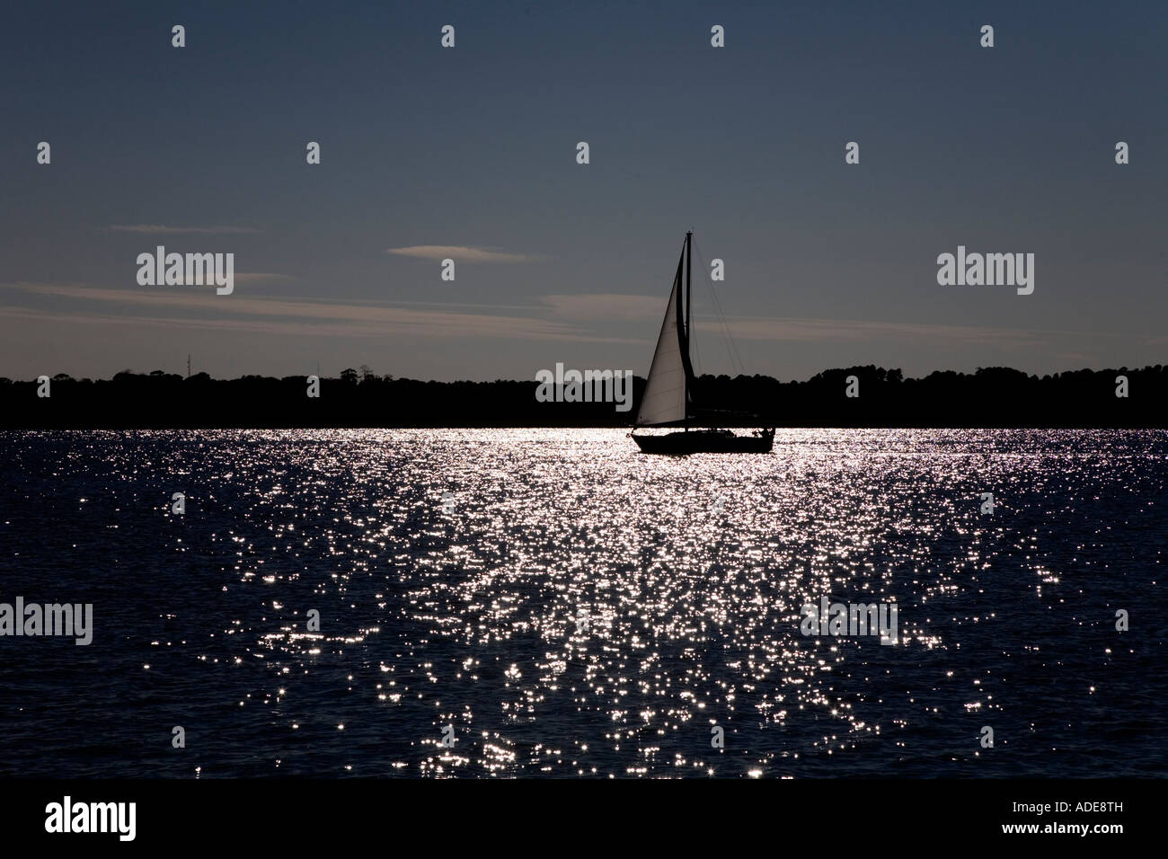 Sailboat crosses the reflection of the moon at night on North River ...