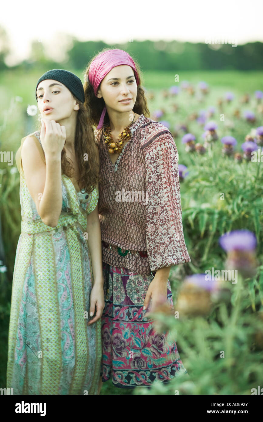 Young hippie women standing in field, one blowing dandelion seeds Stock ...