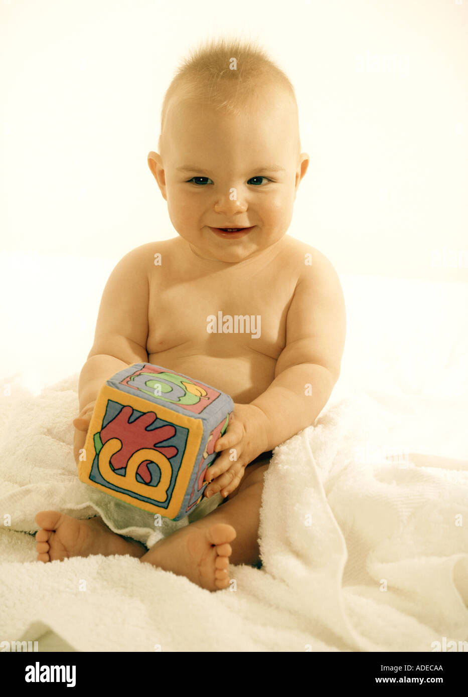 Baby boy sitting up playing with cloth alphabet cube Stock Photo - Alamy
