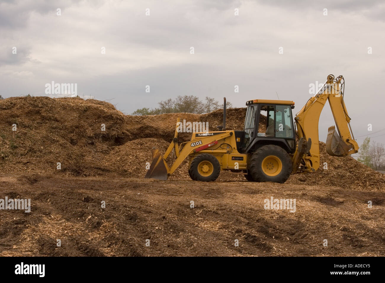 A backhoe ready to load bark mulch for decorative landscaping Stock ...
