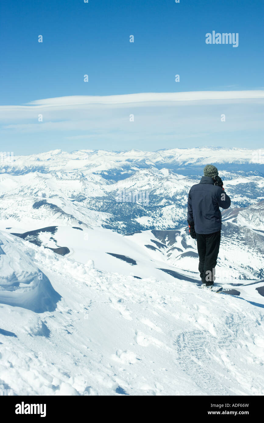 Person overlooking snow covered mountains, using cell phone Stock Photo ...