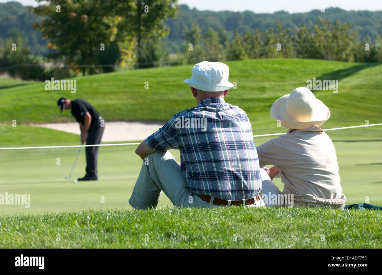 an elderly couple watching professional golfers Stock Photo - Alamy