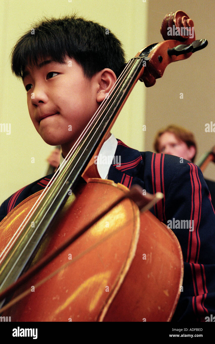 Young oriental boy playing cello in a school orchestra Stock Photo - Alamy