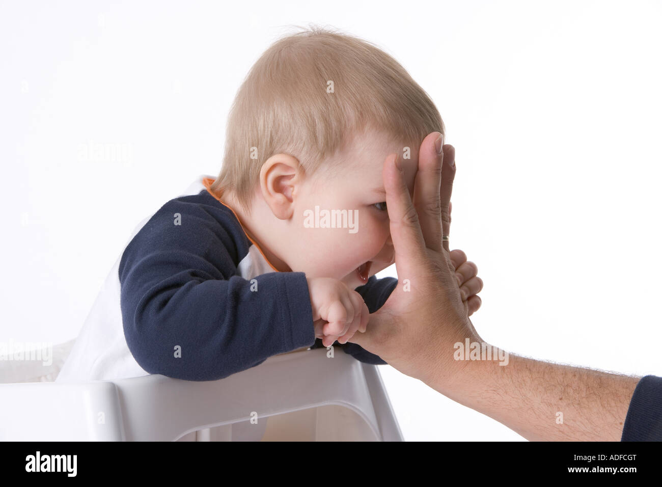 Baby hides behind fathers hand Stock Photo - Alamy