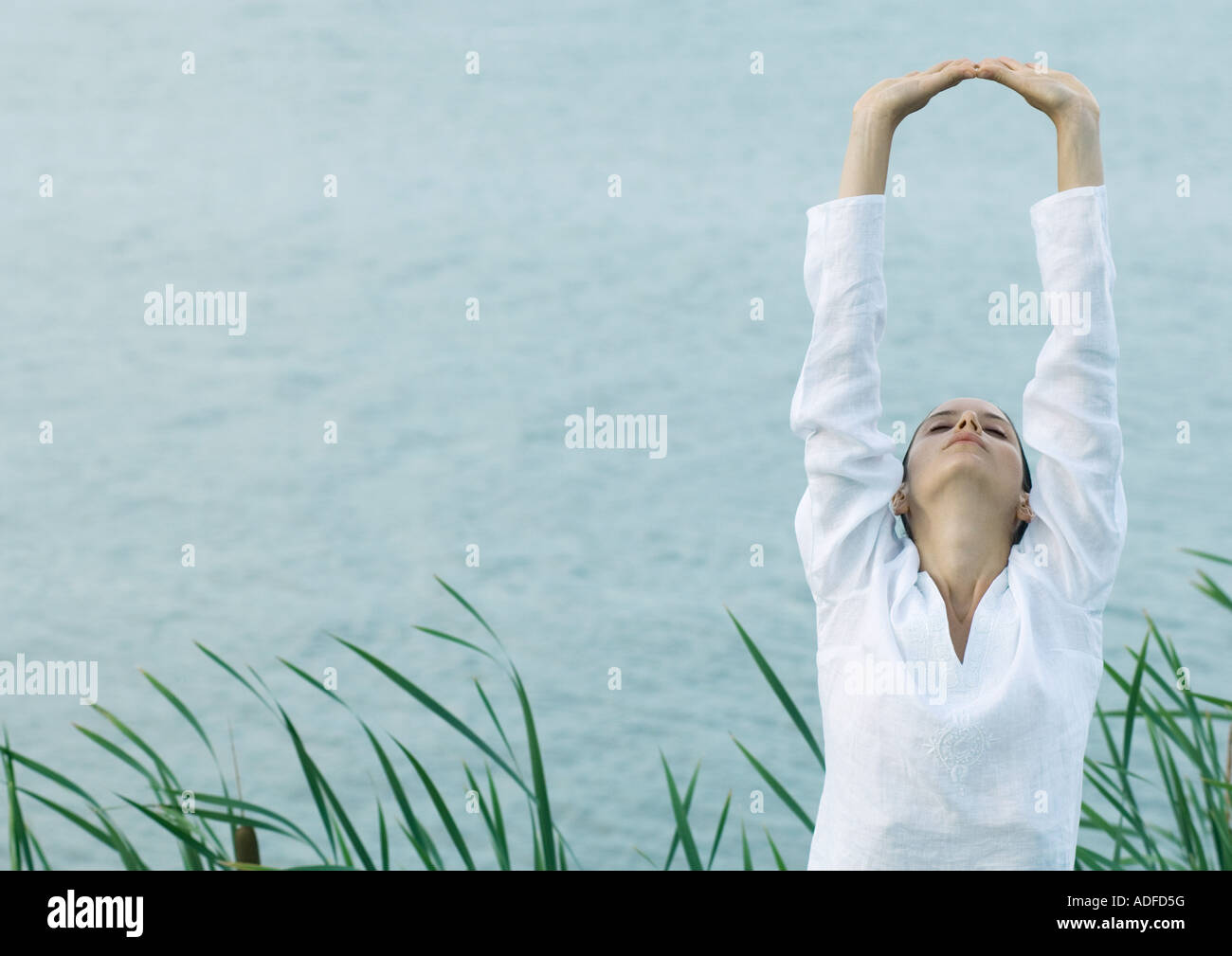 Woman stretching arms over head, lake in background Stock Photo - Alamy