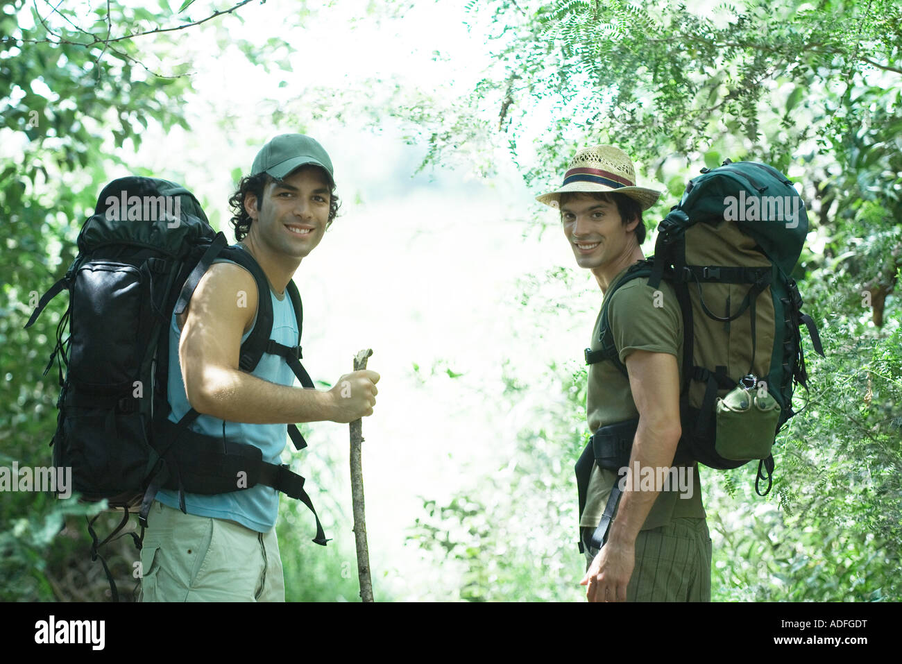 Two hikers standing near edge of forest, looking at camera Stock Photo ...
