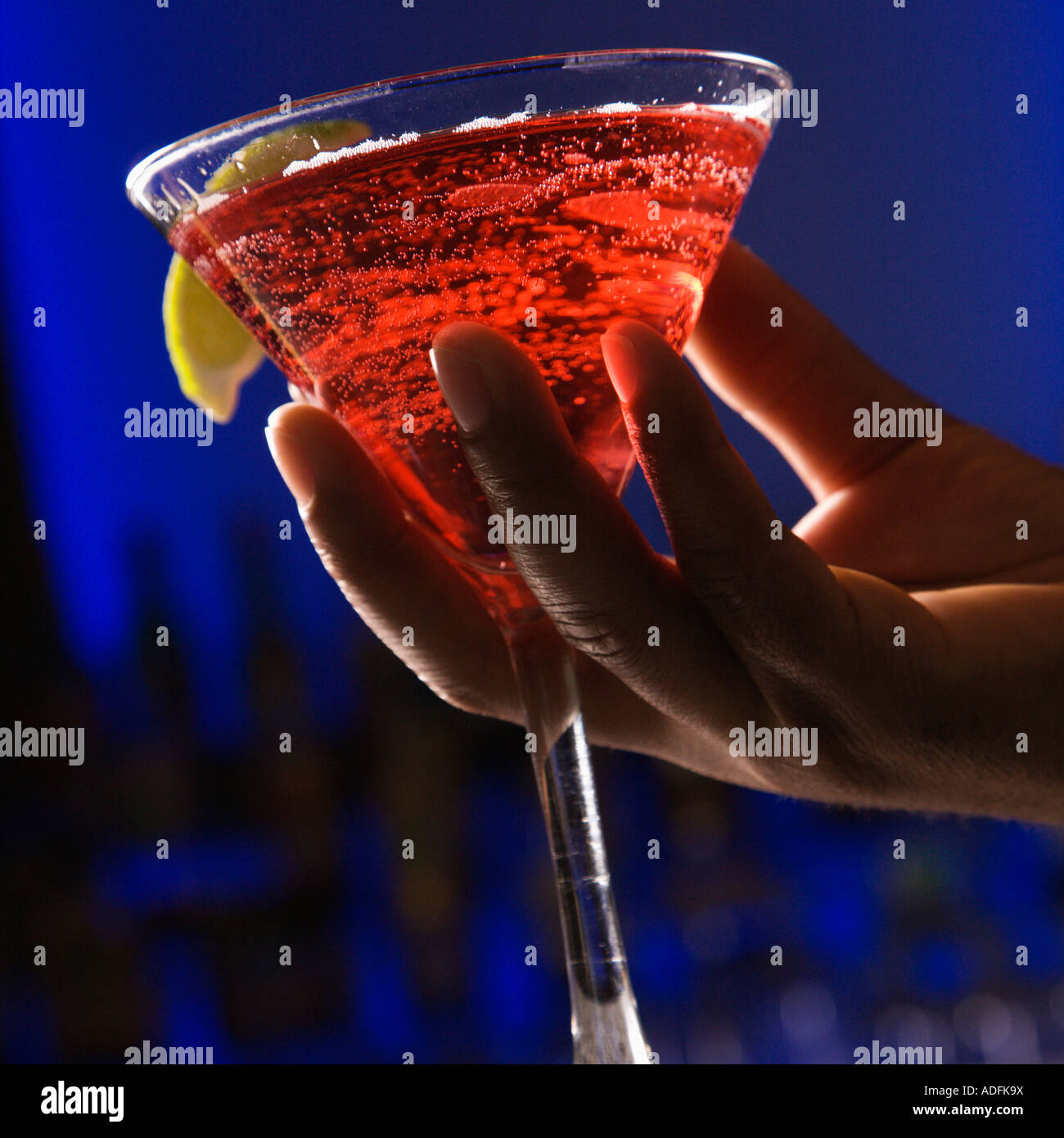 African American male hand holding martini in bar against glowing blue ...
