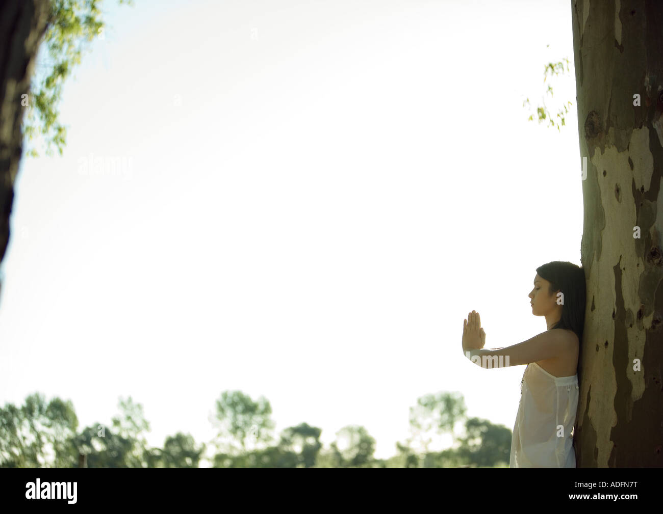 Woman leaning against tree, doing yoga pose Stock Photo - Alamy