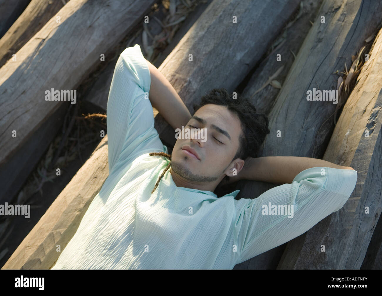Man lying on pile of logs Stock Photo - Alamy
