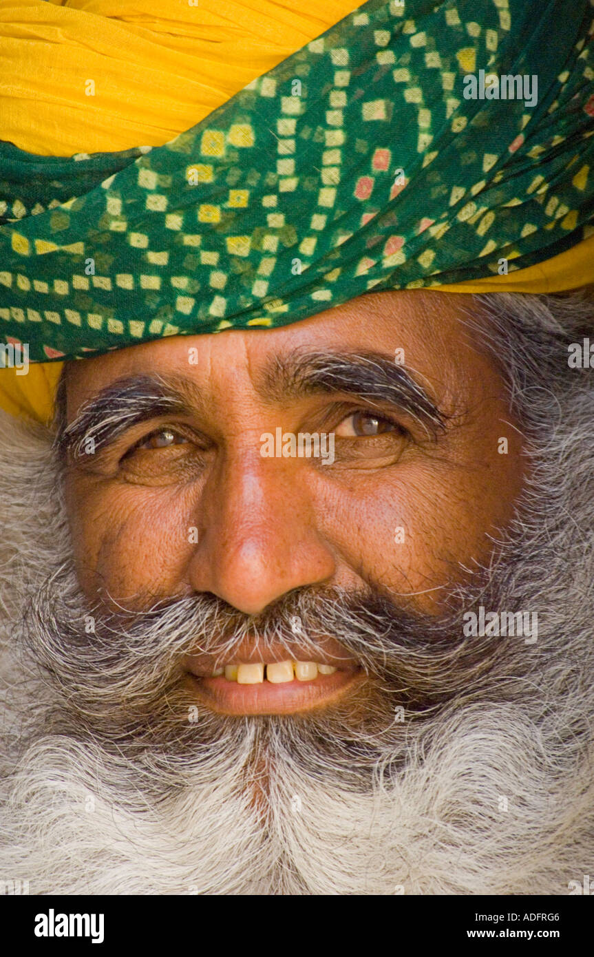 Portrait of a smiling turbaned elderly Indian man with a grey bushy ...